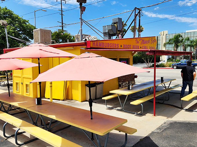 The yellow picnic tables under coral umbrellas aren't just seating—they're front-row tickets to the best show in town: lunch.
