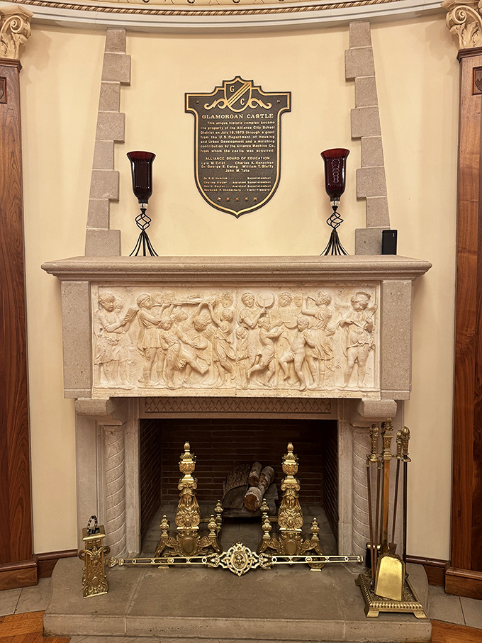 This isn't just a fireplace—it's a masterpiece of carved stone storytelling, framed by brass andirons that have reflected countless flames.