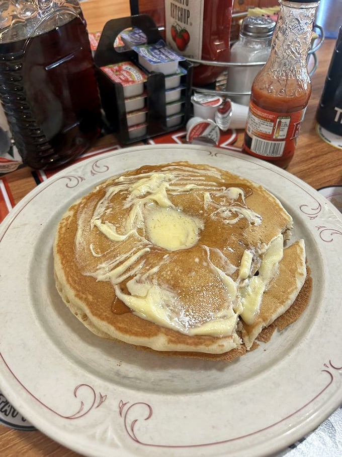 Pancakes aren't just breakfast—they're blank canvases for butter rivers and maple syrup lakes. Pure morning artistry on a classic diner plate.