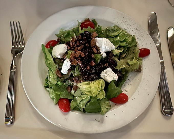 A simple greens salad becomes a canvas of flavors with bright tomatoes and generous crumbles of cheese – proof that sometimes less truly is more.