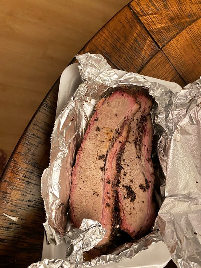 Foil-wrapped brisket revealing that coveted pink smoke ring—evidence of a 14-hour love affair between beef and smoldering wood.