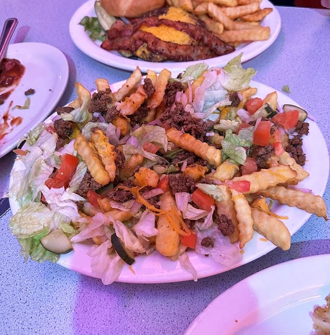 A mountain of fries topped with savory meat and fresh veggies—proof that sometimes the best culinary experiences don't require fancy silverware.
