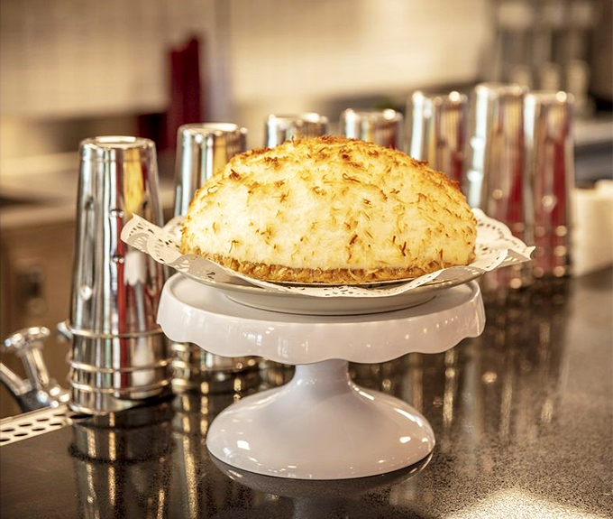 Coconut meringue pie with a crown so high it needs its own atmosphere—a cloud-like topping that's the stuff of dessert dreams.