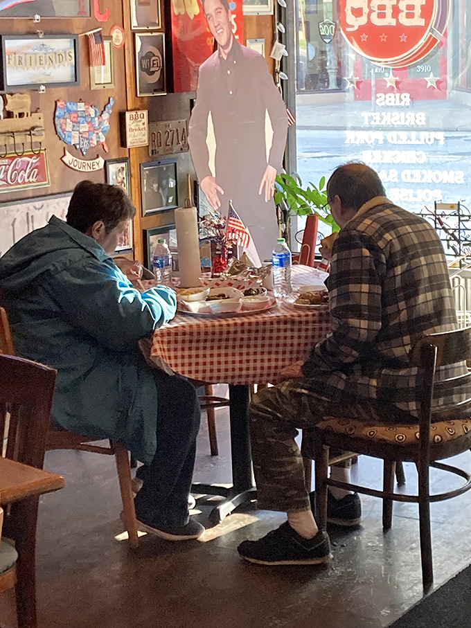 Even cardboard cutouts can't resist joining these diners. The red-checkered tablecloth signals you're in authentic territory—no fancy frills, just serious eating.
