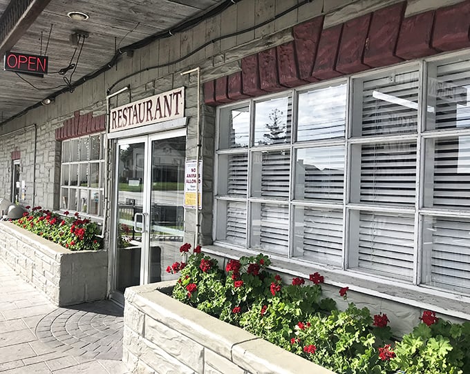 Red geraniums stand guard at the entrance, welcoming hungry travelers to this stone sanctuary of comfort food.