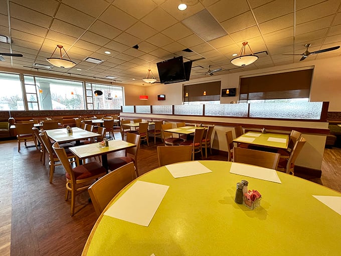 The dining room's layout feels like a choreographed dance between privacy and community, with booths and tables bathed in natural light.