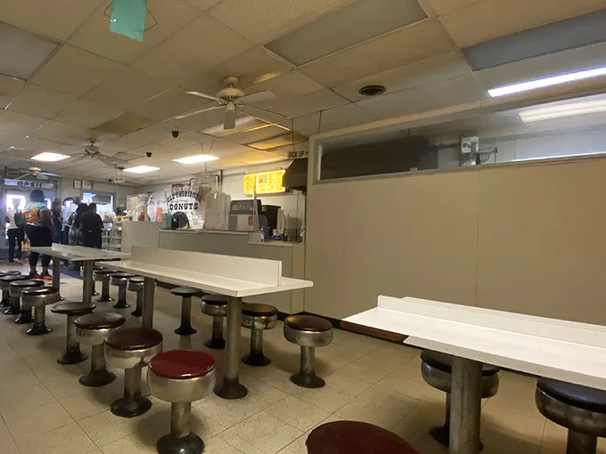 The diner aesthetic remains gloriously unchanged – ceiling fans spinning stories overhead while countertops hold decades of satisfied customer memories.