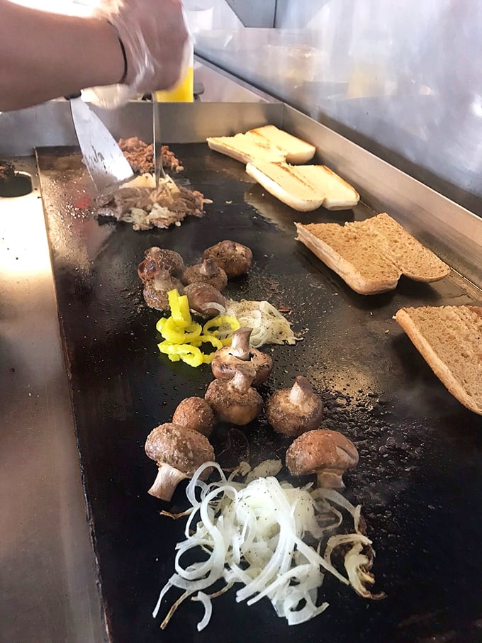 The flat-top ballet—mushrooms, onions, and bread getting the VIP treatment. There's something hypnotic about watching your sandwich come to life.