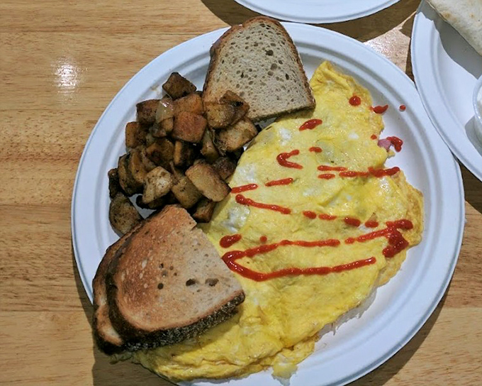 This isn't just an omelet—it's breakfast architecture, with home fries standing guard and toast ready to soak up every last morsel.