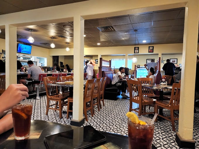 The patterned floor tiles and warm wood tones create a space where conversations flow as freely as the coffee refills.