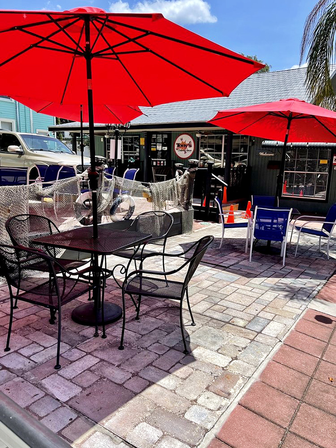 The outdoor seating area offers Florida sunshine with your seafood. Those red umbrellas aren't just for show—they're beacons for hungry travelers.