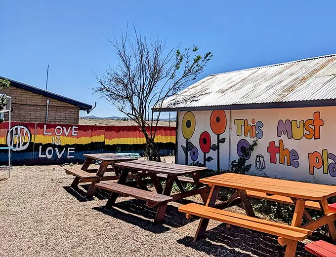 Colorful murals and rustic picnic tables create an inviting oasis in Sonoita's wine country, where western heritage meets artistic spirit.
