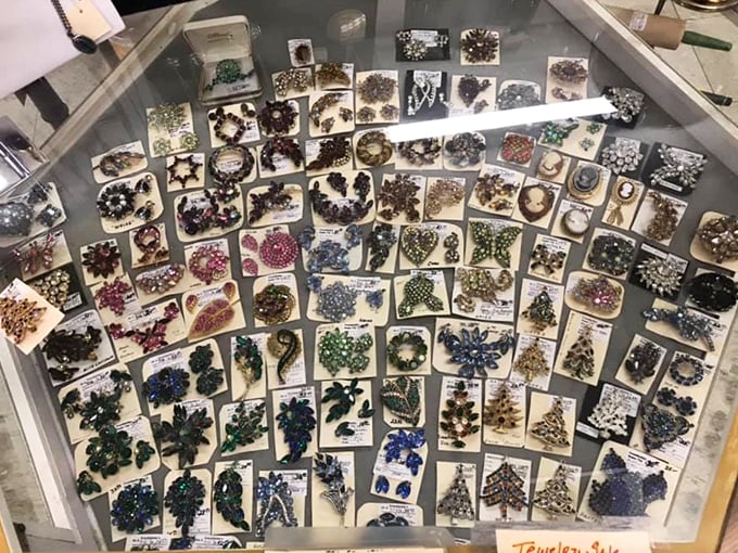 A dazzling constellation of costume jewelry sparkles under glass. Brooches, pins, and earrings arranged like a glittering galaxy of bygone glamour.