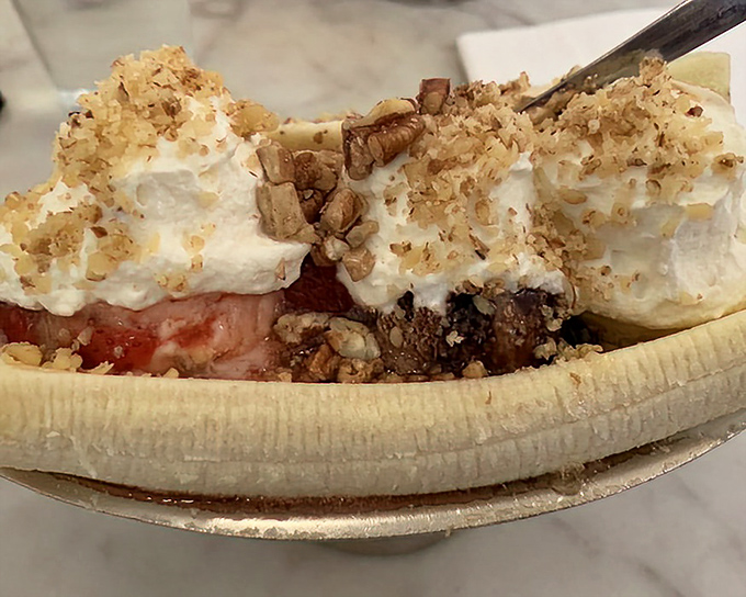 This banana split isn't just dessert—it's a work of art. Whipped cream mountains with nutty avalanches sliding into fruity valleys.