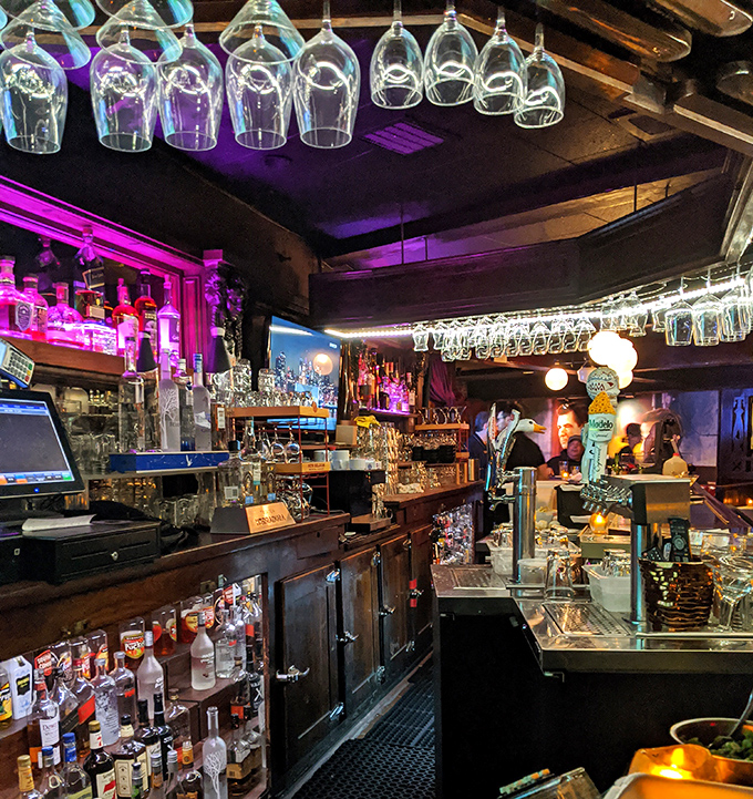 Behind this bar, mixologists craft cocktails that would impress Don Draper himself. The purple lighting adds a modern twist to classic ambiance.