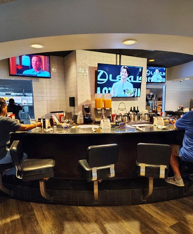The bar counter—where morning mimosas meet coffee connoisseurs under the watchful eye of mounted TVs showing the day's events.