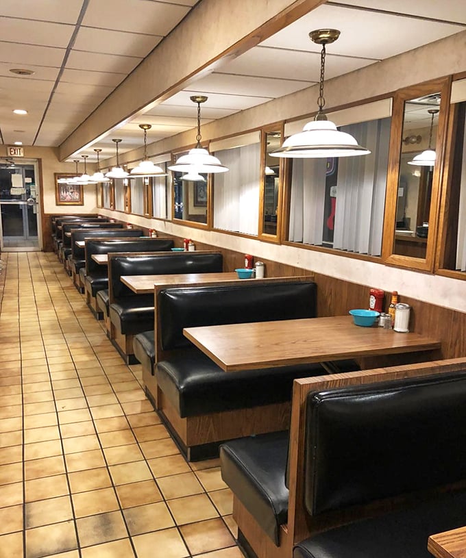 The classic diner booth—where sliding in feels like coming home and every meal tastes better against black vinyl and wood paneling.