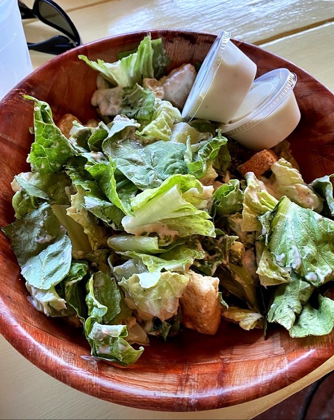 A Caesar salad that Julius himself would approve—crisp romaine dressed in creamy goodness, served in a wooden bowl that whispers "authenticity."