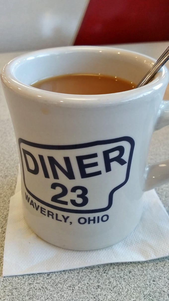 The official chalice of diner culture—a sturdy white mug emblazoned with pride of place. Coffee inside: hot, strong, and judgment-free.