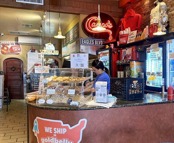 Behind this counter, sandwich artists perform their daily magic. The neon sign glows like a beacon, guiding hungry pilgrims to hoagie heaven.