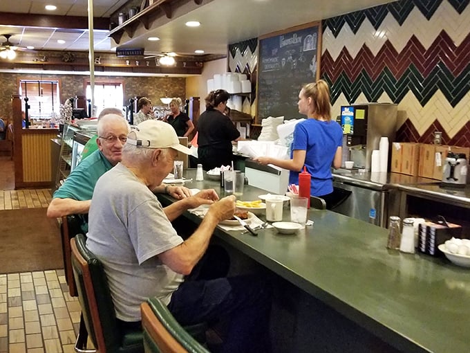Counter dining – where regulars perch like oracles of breakfast wisdom, coffee mugs perpetually half-full, never half-empty.