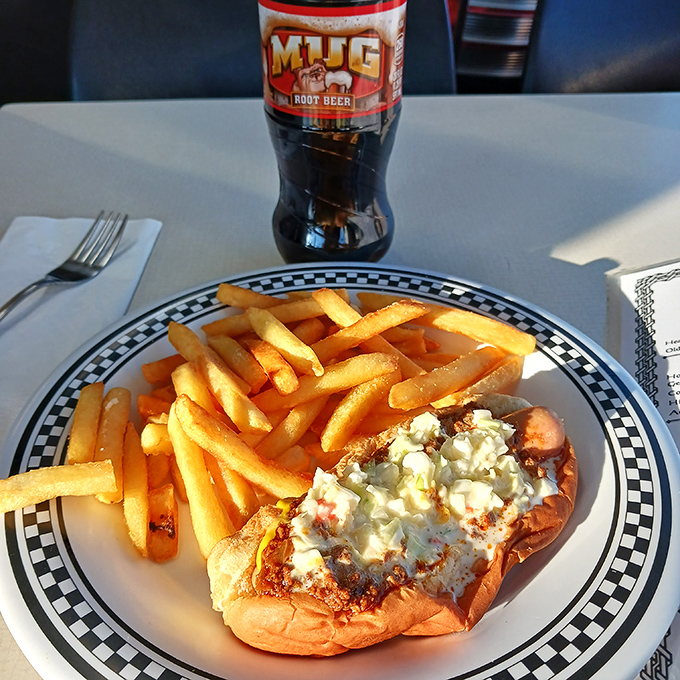 The holy trinity of diner perfection: a loaded dog, golden fries, and an ice-cold Mug Root Beer – America's comfort food trifecta in its natural habitat.