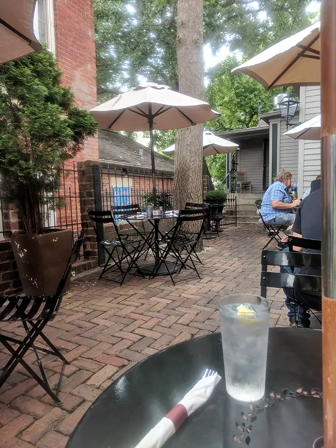 The brick patio—dappled with shade from towering trees—offers the perfect setting for summer sipping and the gentle art of people-watching.