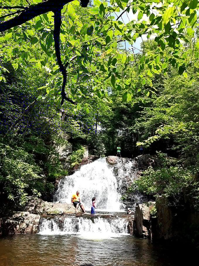 Visitors cool off in the refreshing waters beneath cascading falls that make summer heat completely forgettable.