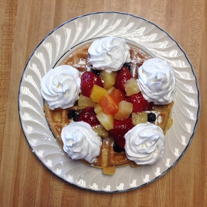 This isn't just a waffle—it's a dessert disguised as breakfast, where fruit provides the alibi and whipped cream seals the deal.