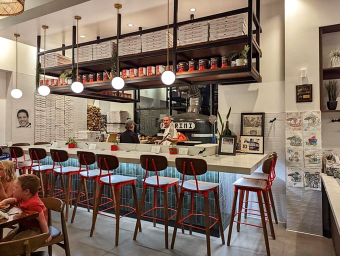 The open kitchen bar seating offers dinner and a show—watch pizza artisans transform simple ingredients into edible masterpieces while you sip your wine.