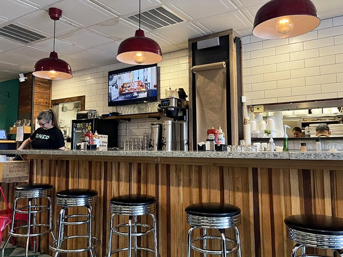 The bar area offers front-row seats to the breakfast ballet. Those red pendant lights aren't just illuminating the space – they're setting the mood.