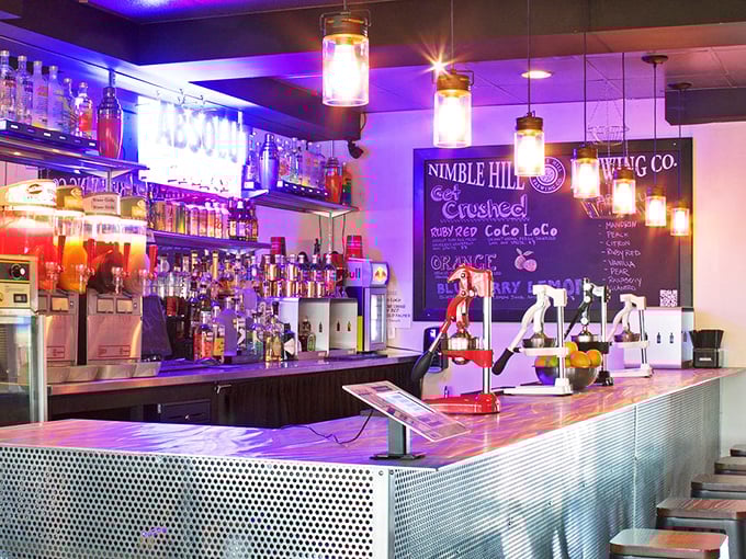 The bar glows with purple ambiance after dark, showcasing local craft beers and spirits waiting to become your new favorite.