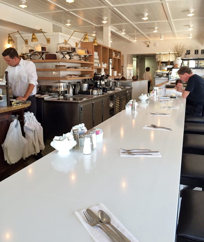 The counter – where coffee cups are never empty and servers remember how you take your eggs better than your spouse does.