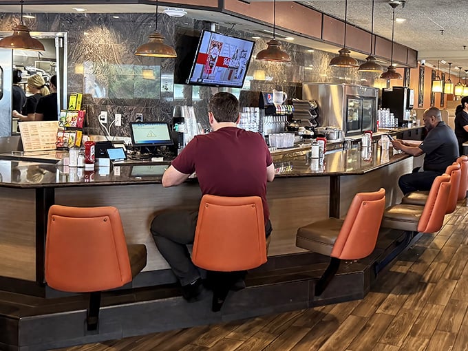 The counter – where solo diners become temporary family, watching the rhythmic ballet of short-order cooking while perched on coral-colored thrones.
