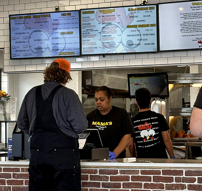 Behind the counter, where fried chicken alchemy happens daily. Those "Mama Knows Best" shirts aren't just cute—they're stating documented facts.