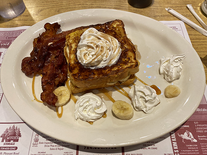 French toast that makes you question every other breakfast decision you've ever made – crowned with whipped cream and surrounded by bacon because balance is important.