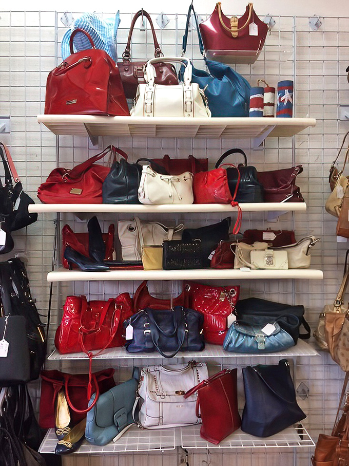 Handbag heaven arranged by color—a leather rainbow for the accessory enthusiast. Your next statement piece is hiding here.
