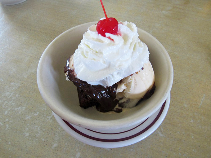 Hot fudge sundae simplicity: vanilla ice cream, chocolate sauce, whipped cream, and that essential cherry on top—childhood in a bowl.