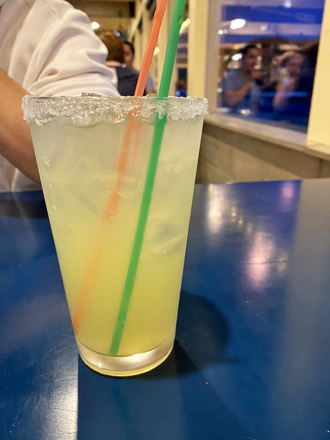 A salt-rimmed margarita with colorful straws stands ready for sipping while watching waves crash. Coastal drinking at its finest—refreshing, bright, and vacation-mandatory.