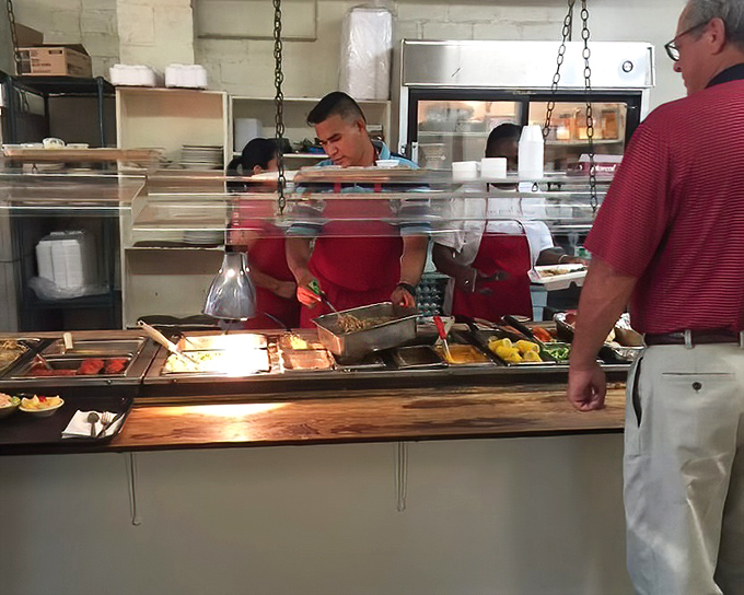 The serving line – where the staff's practiced hands have been dishing out Southern classics with mathematical precision for decades.