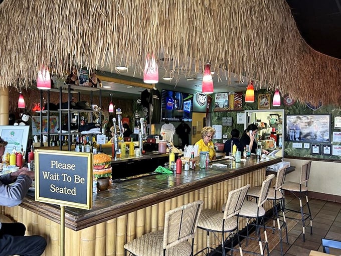 The tiki bar isn't just decoration – it's the command center where burger magic happens beneath strings of colorful lights.