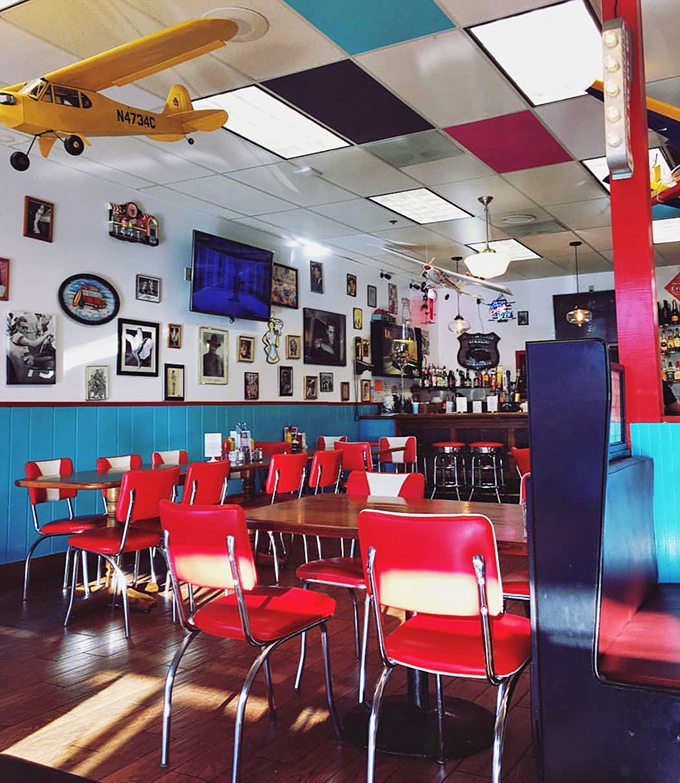 Sunlight streams through windows illuminating a diner straight from American mythology. Those red chairs aren't just seating – they're invitations to join the story. 