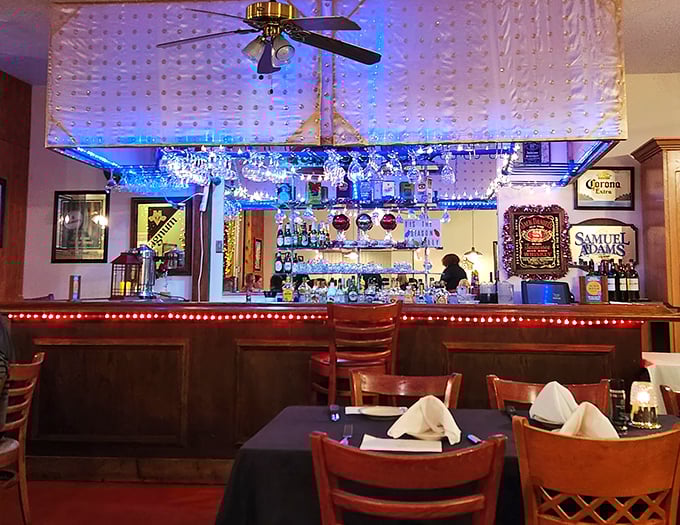 The bar gleams with blue lights and promise, a watering hole where stories get better with each telling and nobody rushes you through your bourbon.