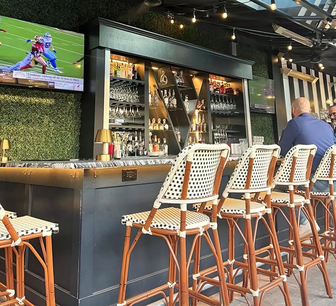 The bar area—where solo diners become temporary friends and bartenders double as therapists. Sports on TV, spirits on shelves.