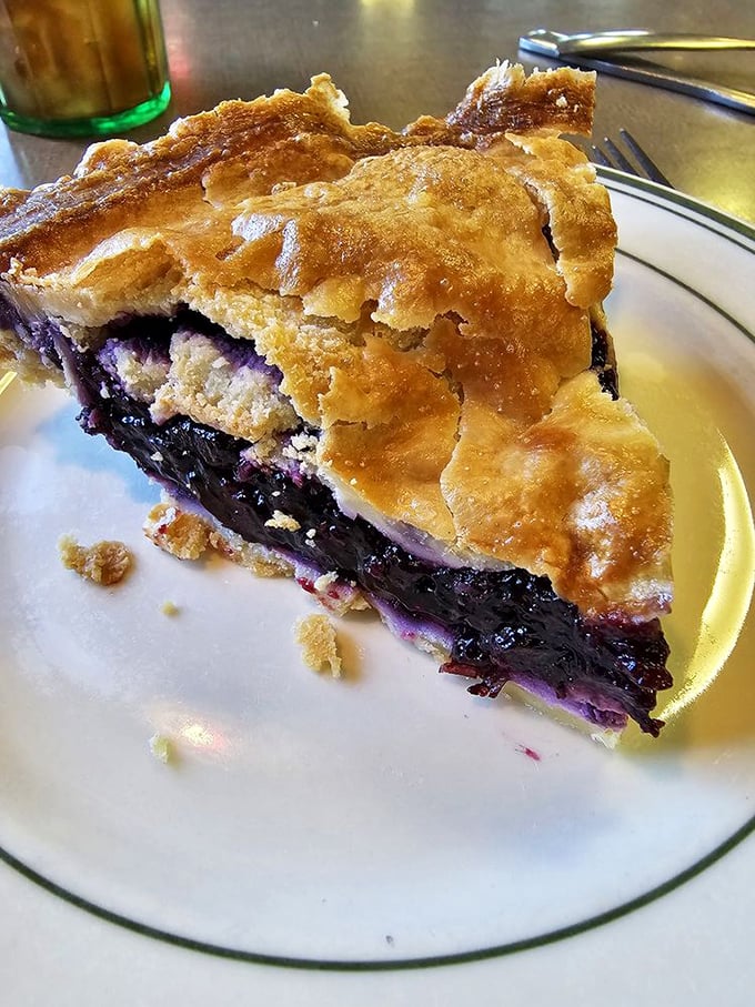 Blueberry pie with a crust so flaky it should be illegal. Those deep purple berries aren't just fruit—they're nature's candy wrapped in buttery pastry perfection.
