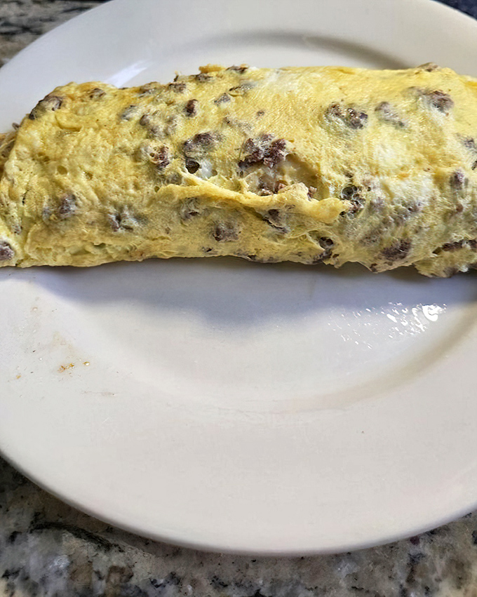 This omelet doesn't just contain cheese and meat—it enfolds them in a fluffy yellow embrace that makes you forget all other breakfast options.