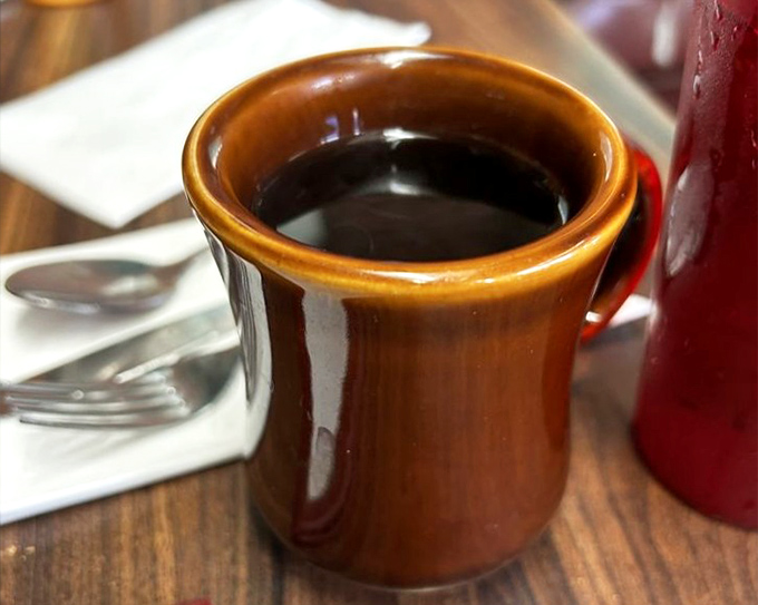That brown ceramic mug isn't just holding coffee—it's holding the fuel that's powered American dreams and morning deadlines for generations.