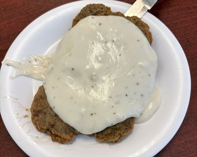 Country fried steak swimming in gravy – the kind of plate that makes cardiologists nervous and customers happy.