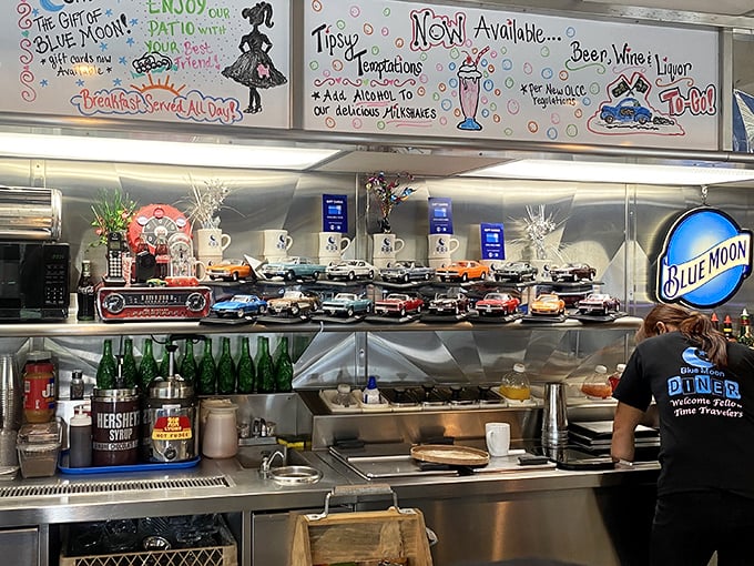 Behind the counter, where the magic happens. That collection of model cars isn't just decoration – it's a timeline of American automotive history.