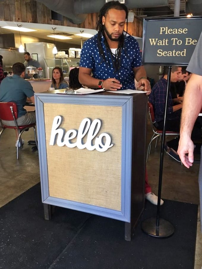 The host stand's cheerful "hello" sign sets the tone for the warm welcome that awaits—your first hint that this isn't just another breakfast joint.